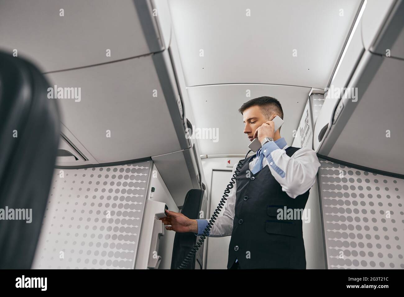 Flight attendant talk on board phone in airplane Stock Photo - Alamy