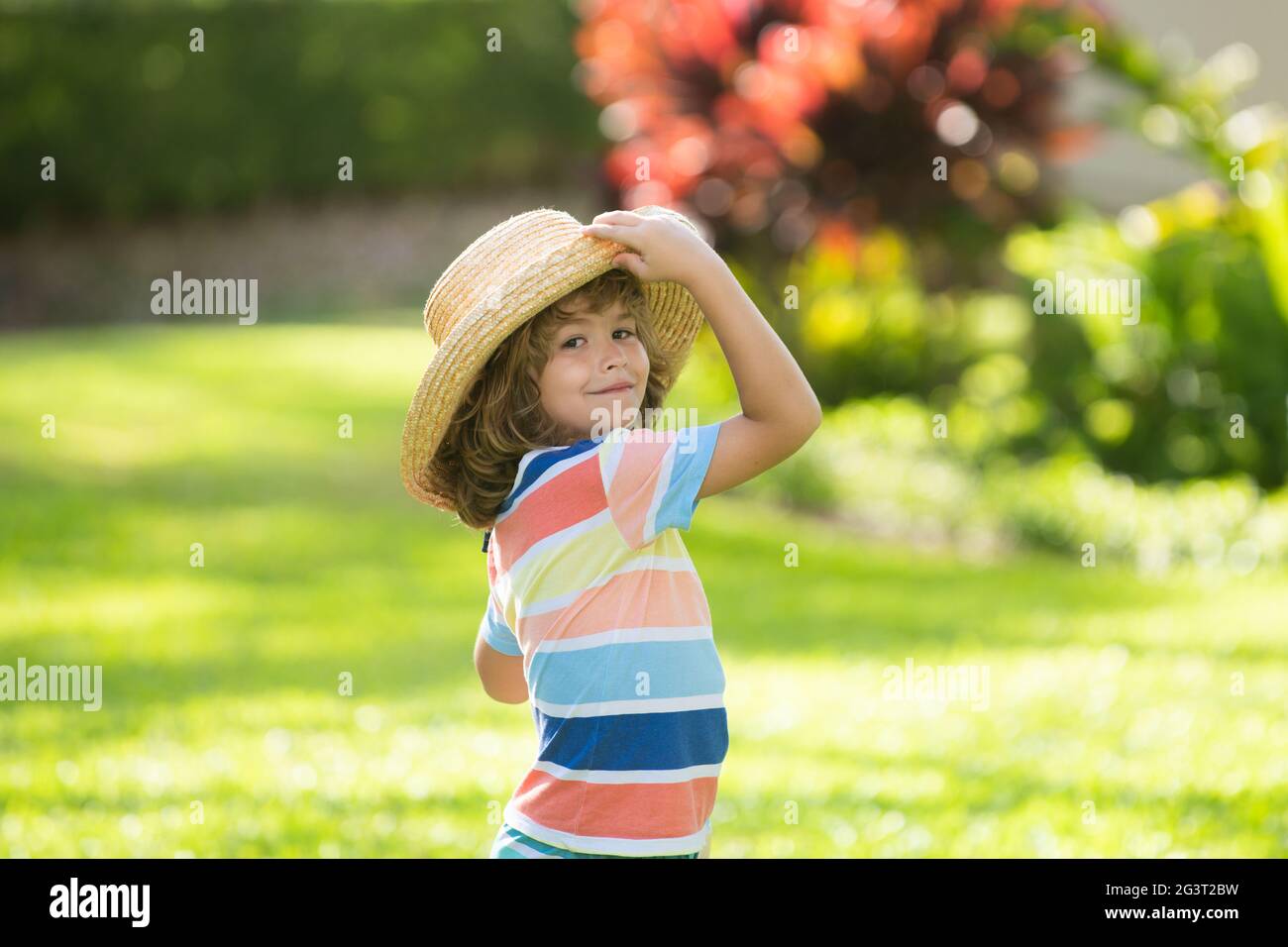 Portrait of a cute little child in straw hat in summer nature park ...