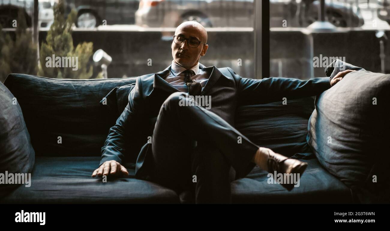 Successful Businessman sits at sofa in business center. Front view of ...