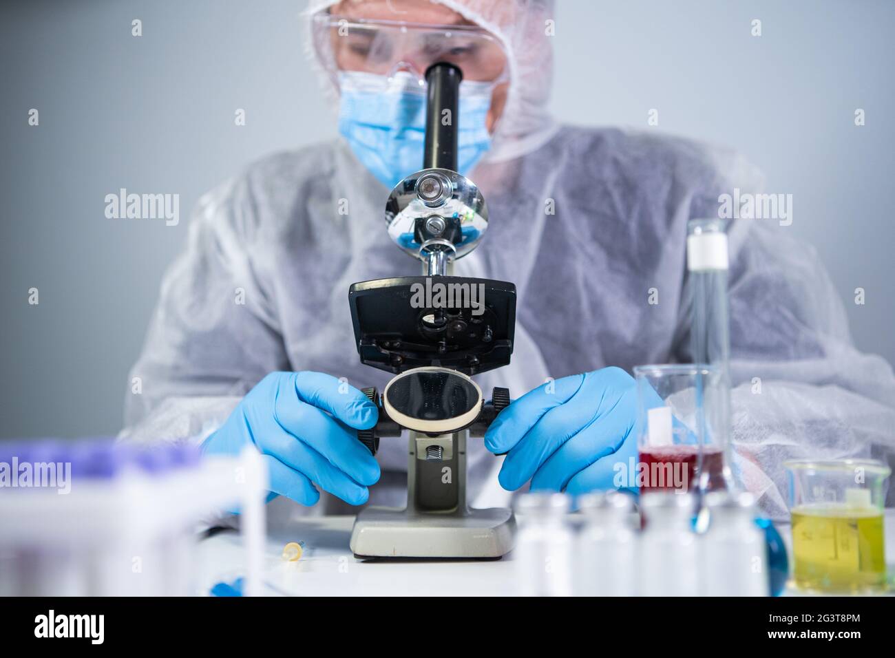 Scientist examining sample with a microscope, doing medical research in ...