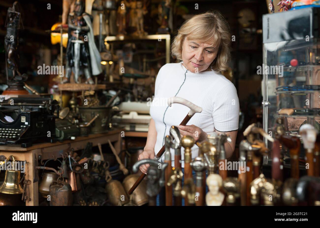 Senior woman chooses rare walking stick at flea market Stock Photo - Alamy