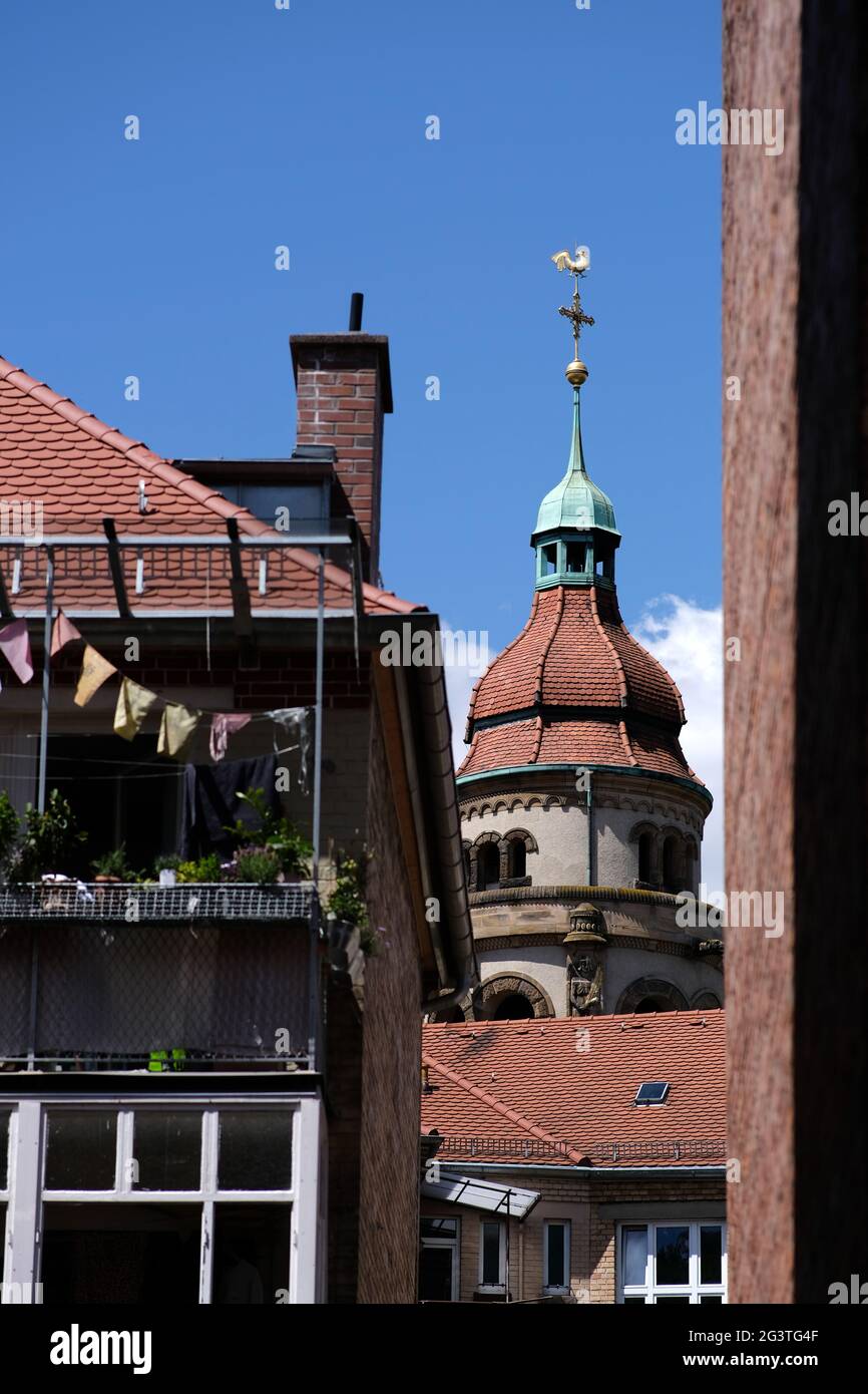 Vertical shot of a church tower behind buildings Stock Photo - Alamy