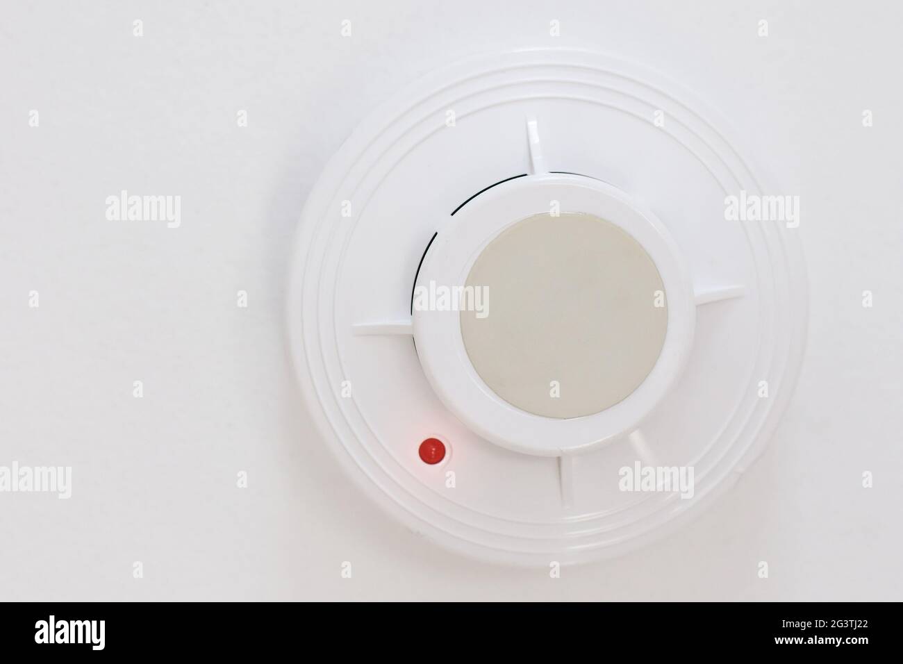 A smoke detector hangs on the white ceiling. Fire prevention device in ...