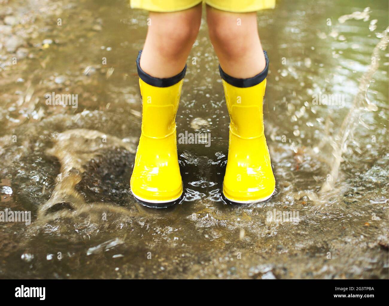 Little girl wearing yellow boots in rainy day Stock Photo - Alamy