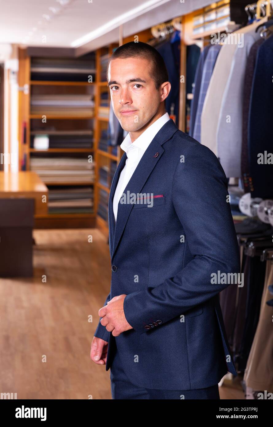 Positive male customer choosing fashion suit in mens store Stock Photo ...