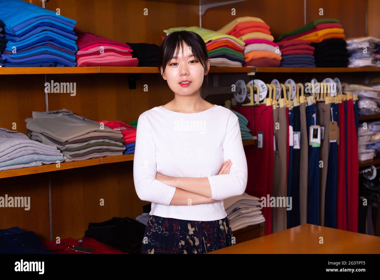 Chinese female shopping assistant offering various shirt in men cloths ...