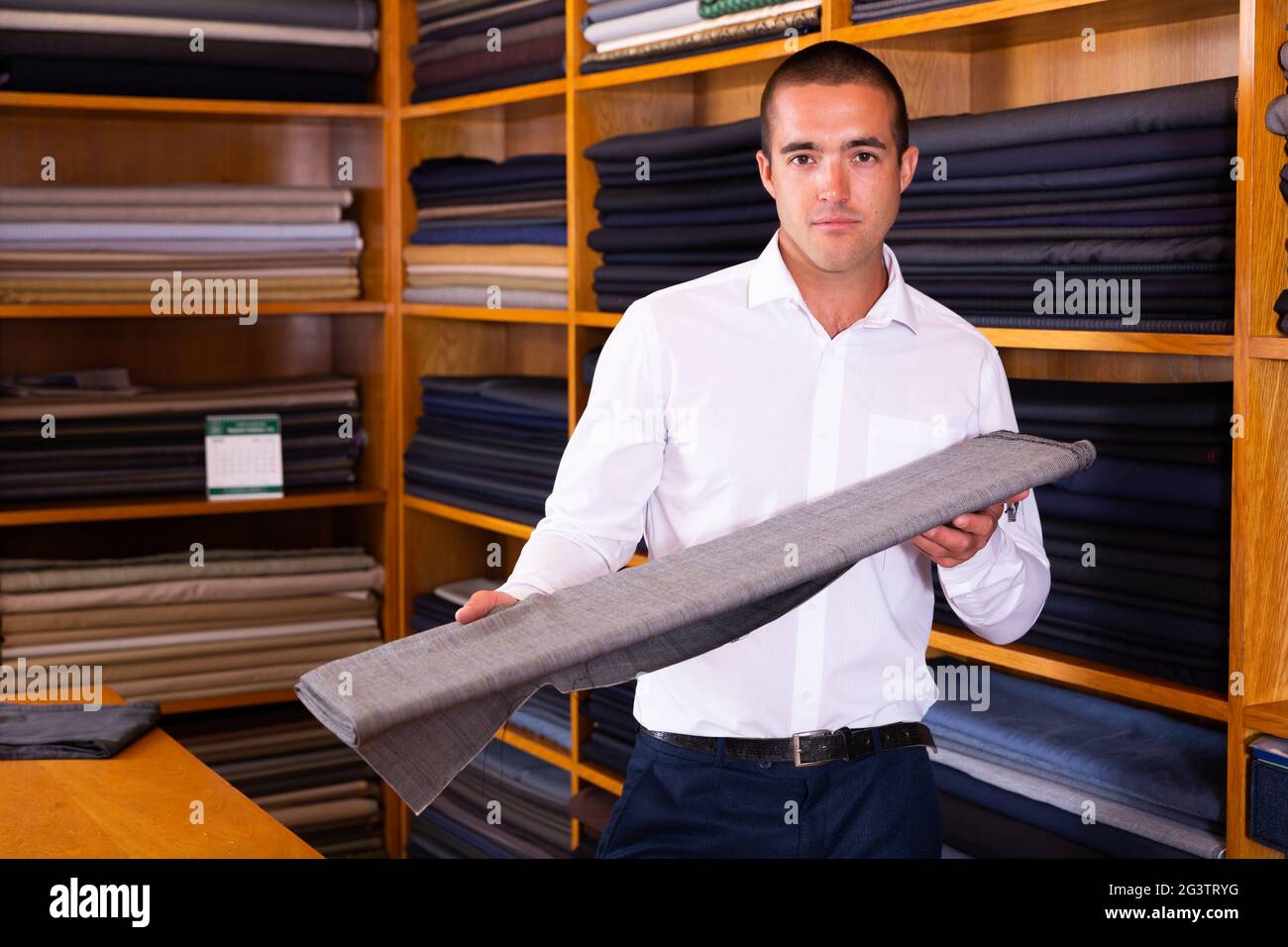 Male seller demonstrates various fabrics in store Stock Photo - Alamy