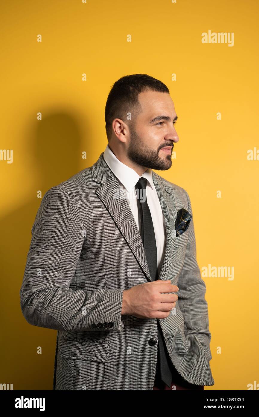 Handsome smiling young man wearing grey suit with one hand lifted ...