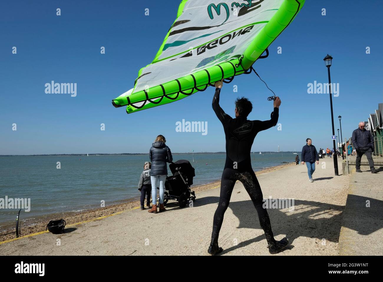 Breeze catches a man's green white kite surfing canopy on revetment ...