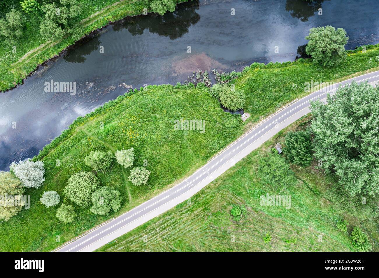 curved bike lane pass through green meadow near river. aerial view from ...