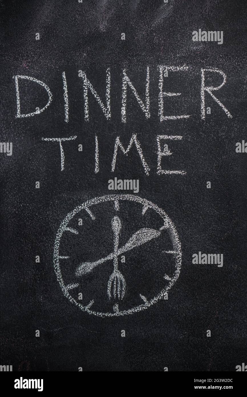 Dinner time text with clock on black chalkboard Stock Photo - Alamy