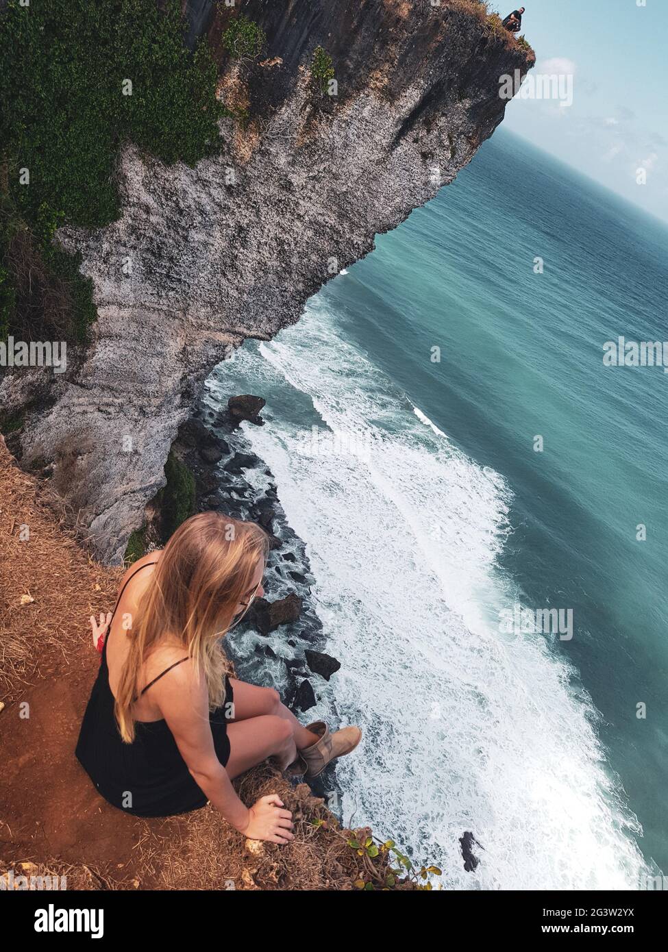Pretty woman tourist sitting on the cliff Stock Photo - Alamy