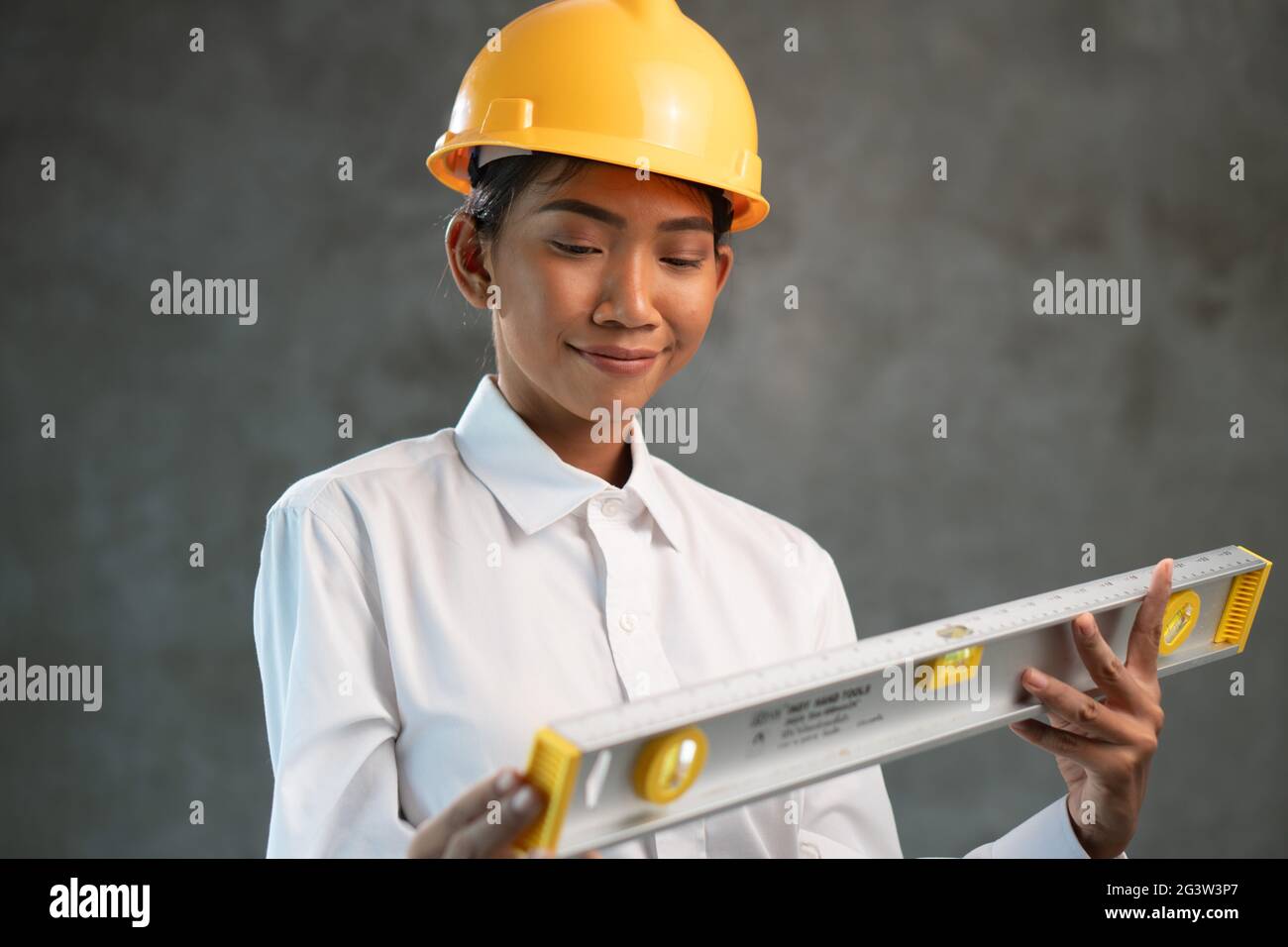 Portrait of attractive Asian woman engineer with building level over ...