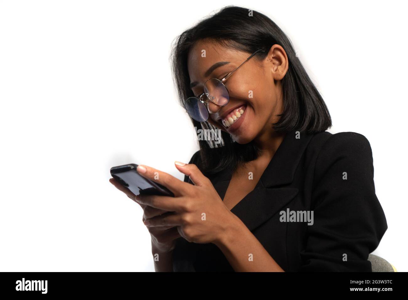 Attractive young Asian business woman smiling while texting on mobile phone isolated over light ...