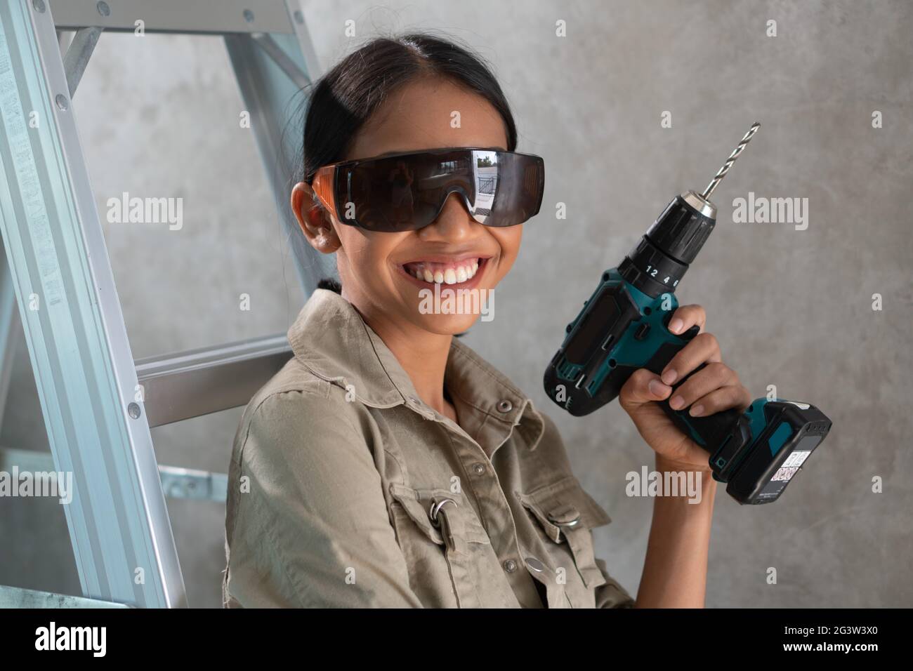 Portrait of attractive young girl builder with drill standing on the ...