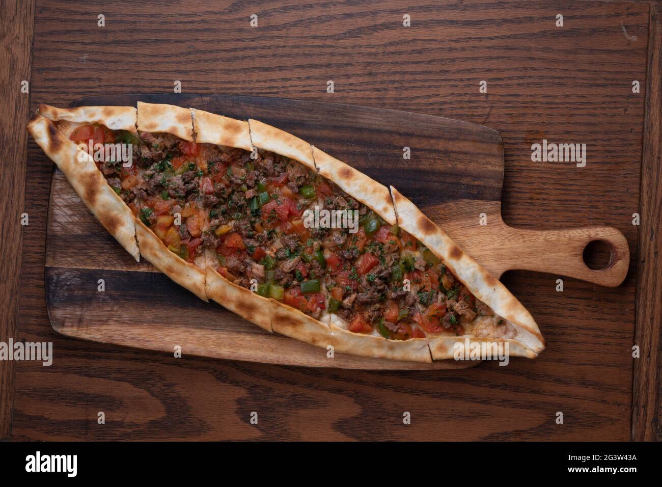 Turkish pide with beef and vegetables on wooden table Stock Photo - Alamy