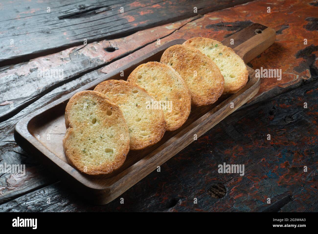 Toasted baguette slices on rustic wooden kitchen table Stock Photo - Alamy