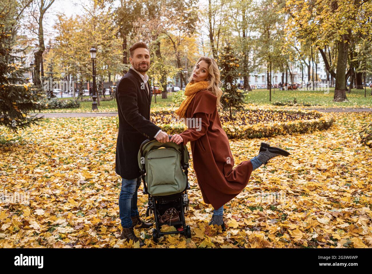Happy family with a newborn baby in a stroller walking in an autumn ...