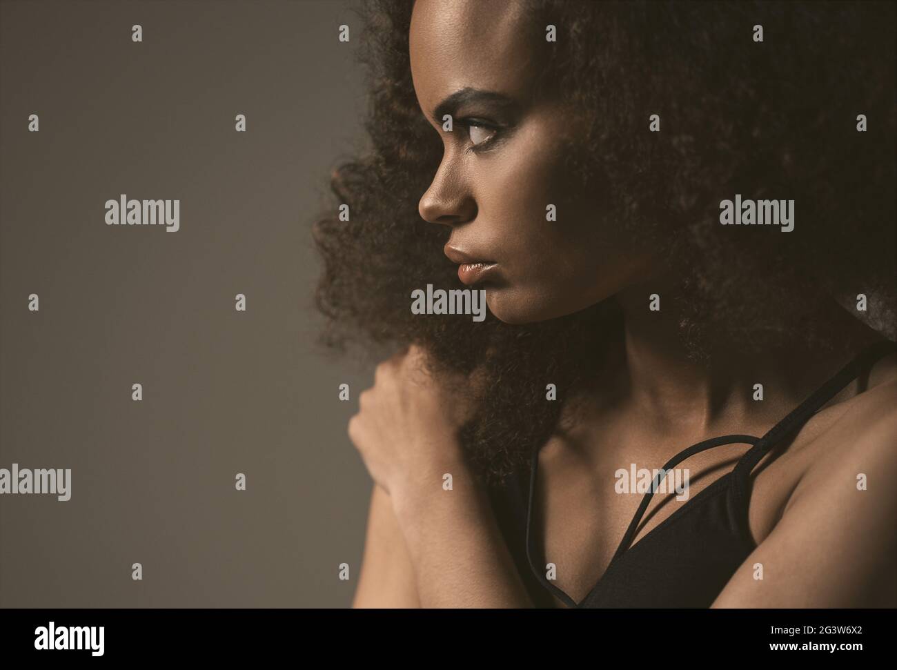 Tender African American girl standing in black top isolated on grey ...