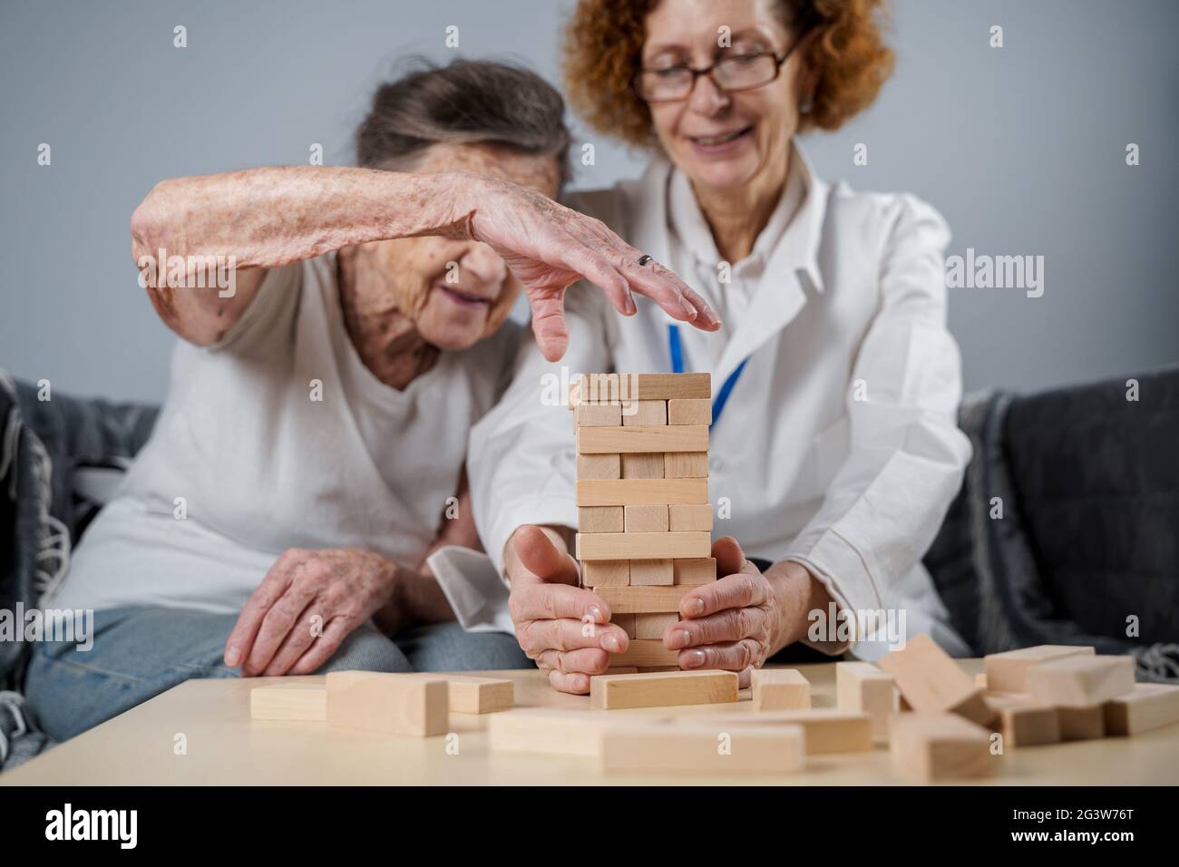 Senior woman practice skills, build wooden blocks, build tower and try ...
