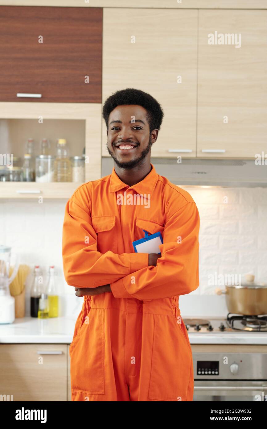 Portrait of cheerful young Afro American plumber with badge on chest ...