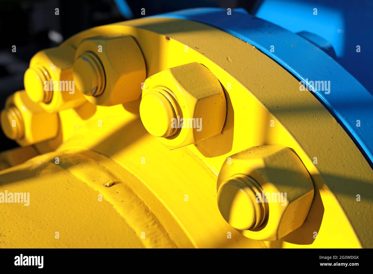 Two blue and yellow gas pipes are connected by large bolts and nuts ...