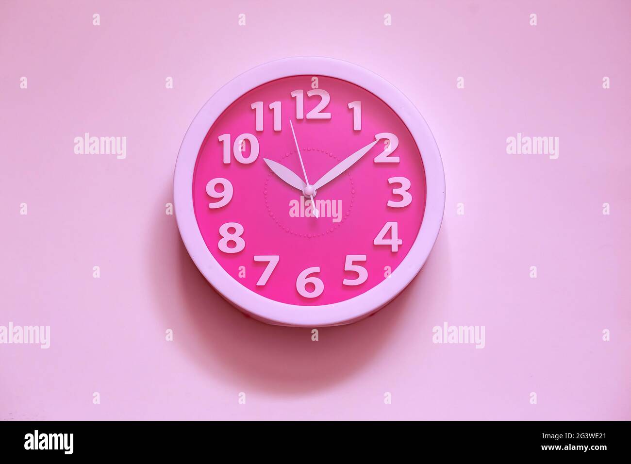 Pink clock on pink painted wall. Minimal time concept. Chrismas eve or ...