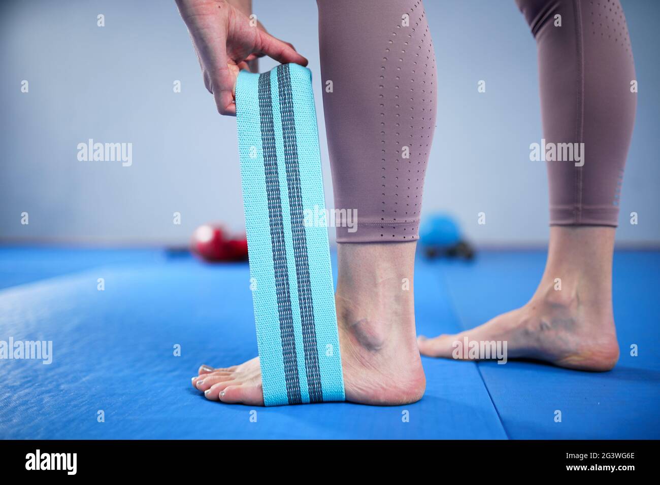 Athletic woman in sportswear barefoot using thick elastic fabric ...