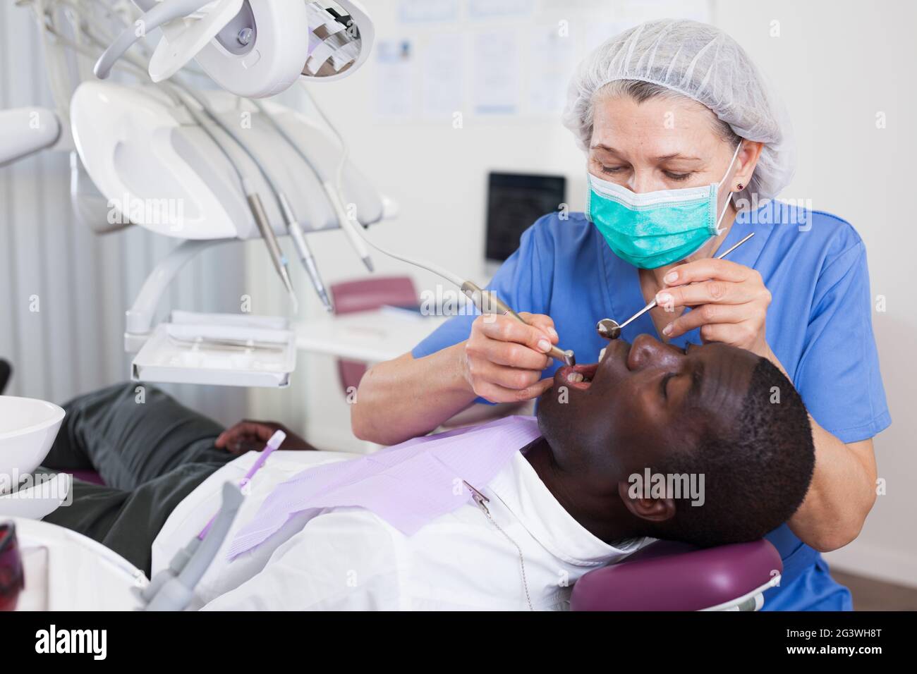 Dentist professional filling teeth for man patient sitting in medical ...