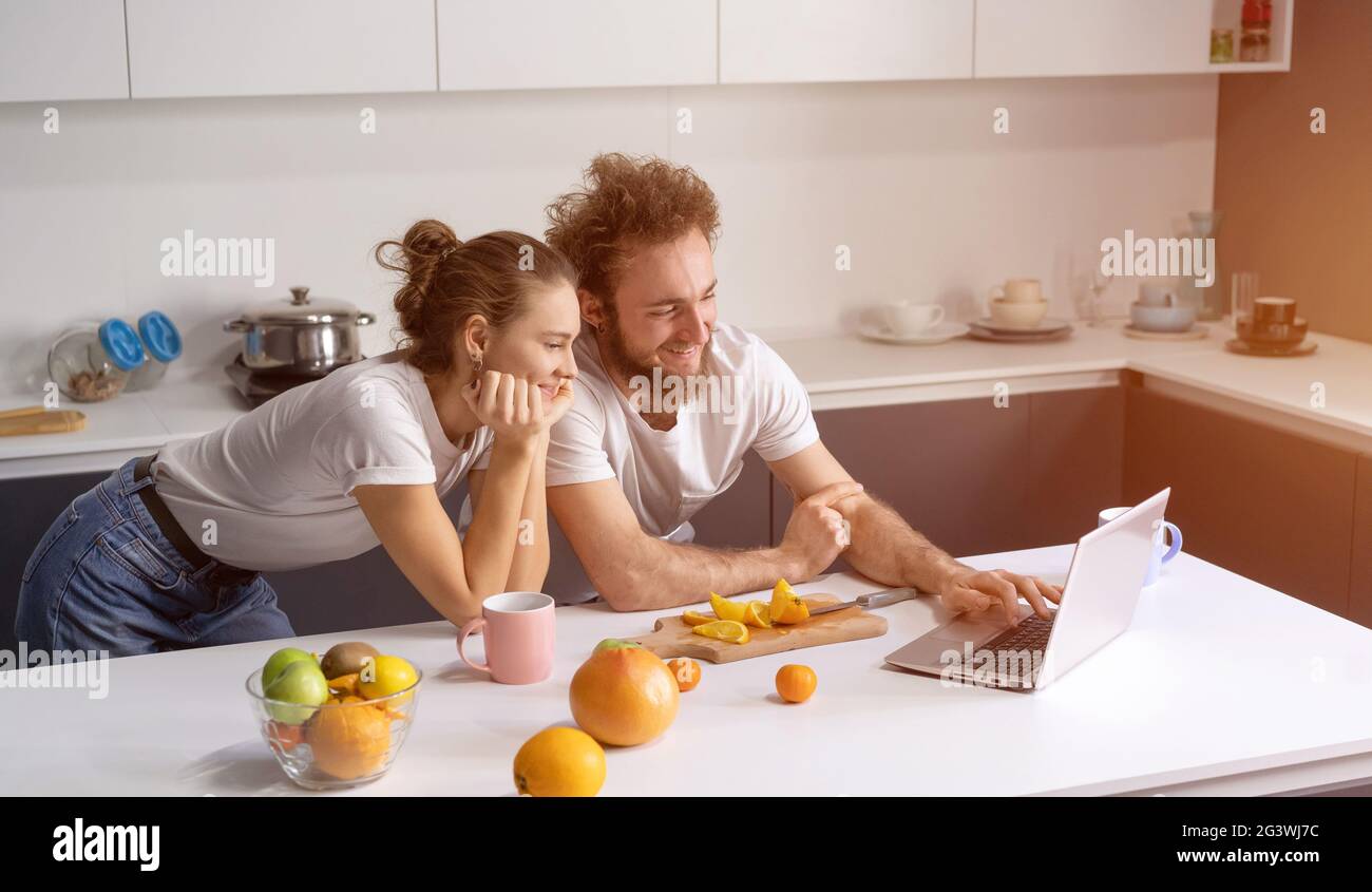 Young couple cooking healthy food in kitchen at home. Girl leaned on ...