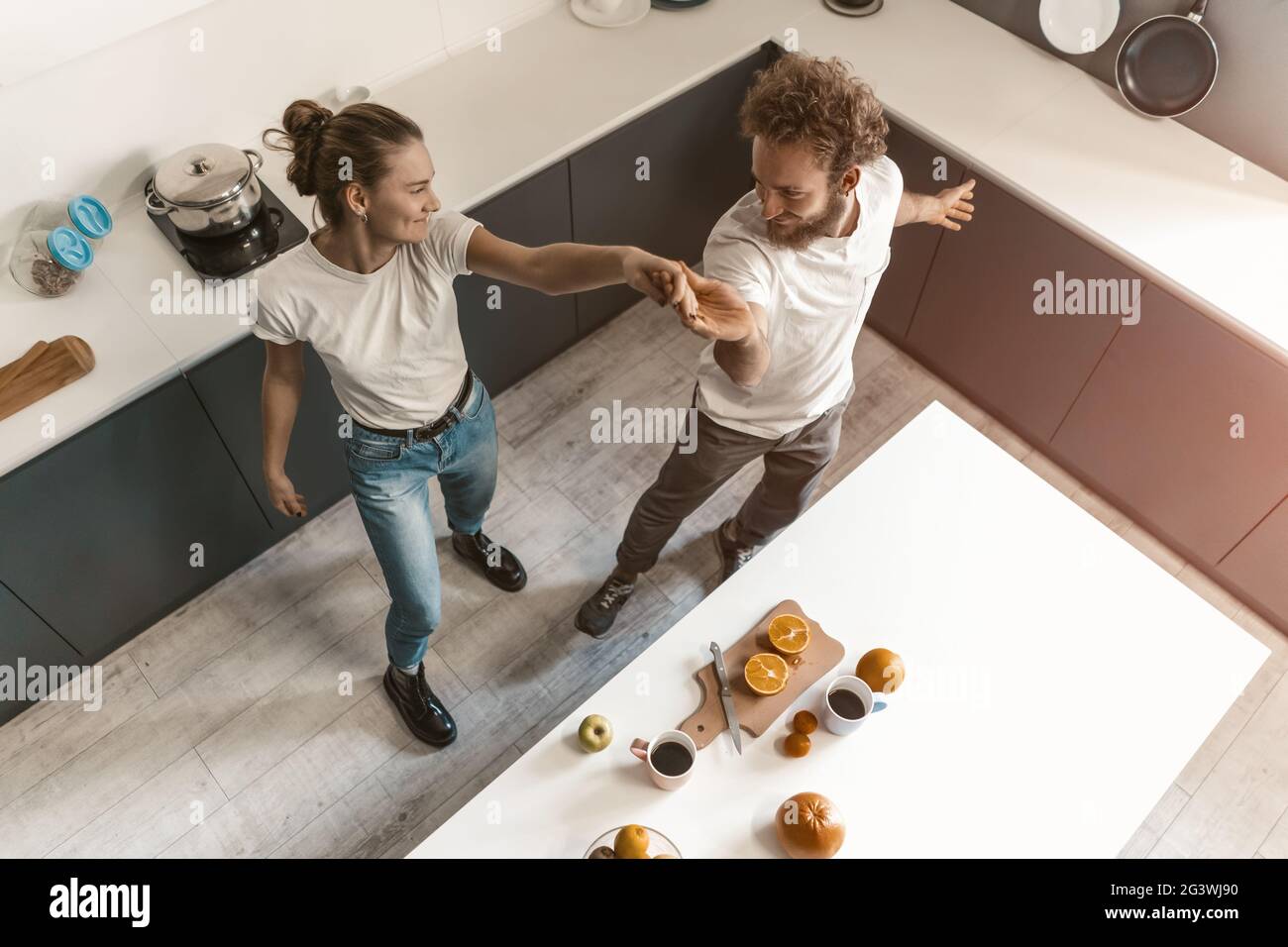 Top view. Young couple dancing in kitchen wearing casual clothes while ...