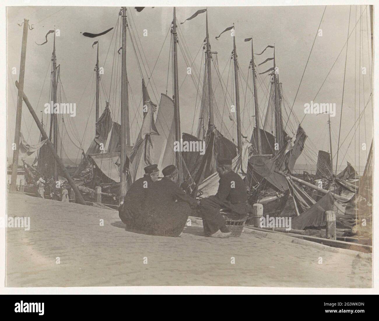 Three men in Volendam traditional costume sitting on a quay. Part of ...