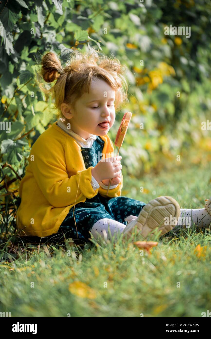 cute baby girl in autumn park eating lollipop Stock Photo - Alamy