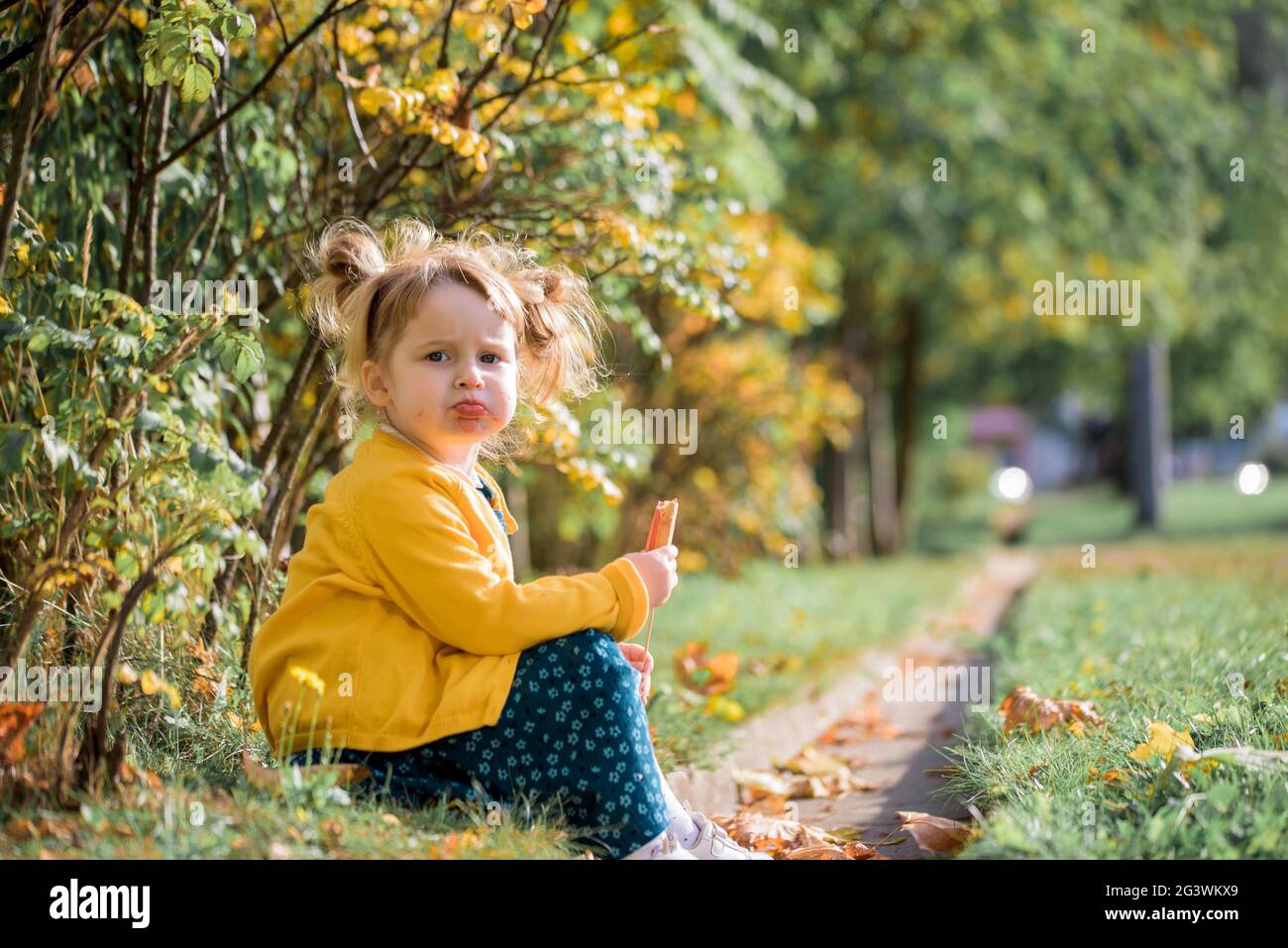 cute baby girl in autumn park eating lollipop Stock Photo - Alamy