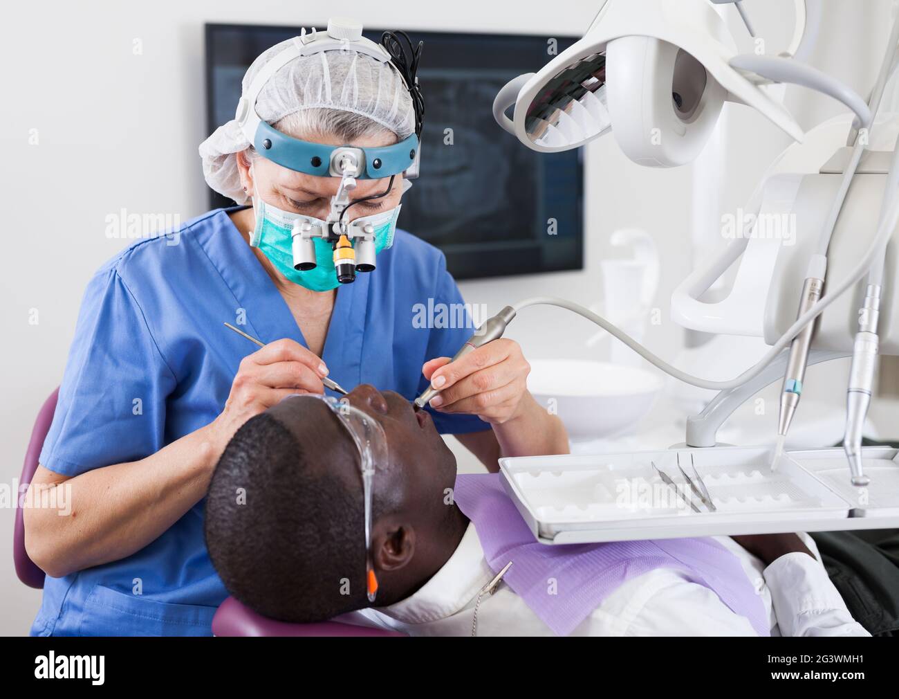 Dentist professional filling teeth for man patient sitting in medical ...