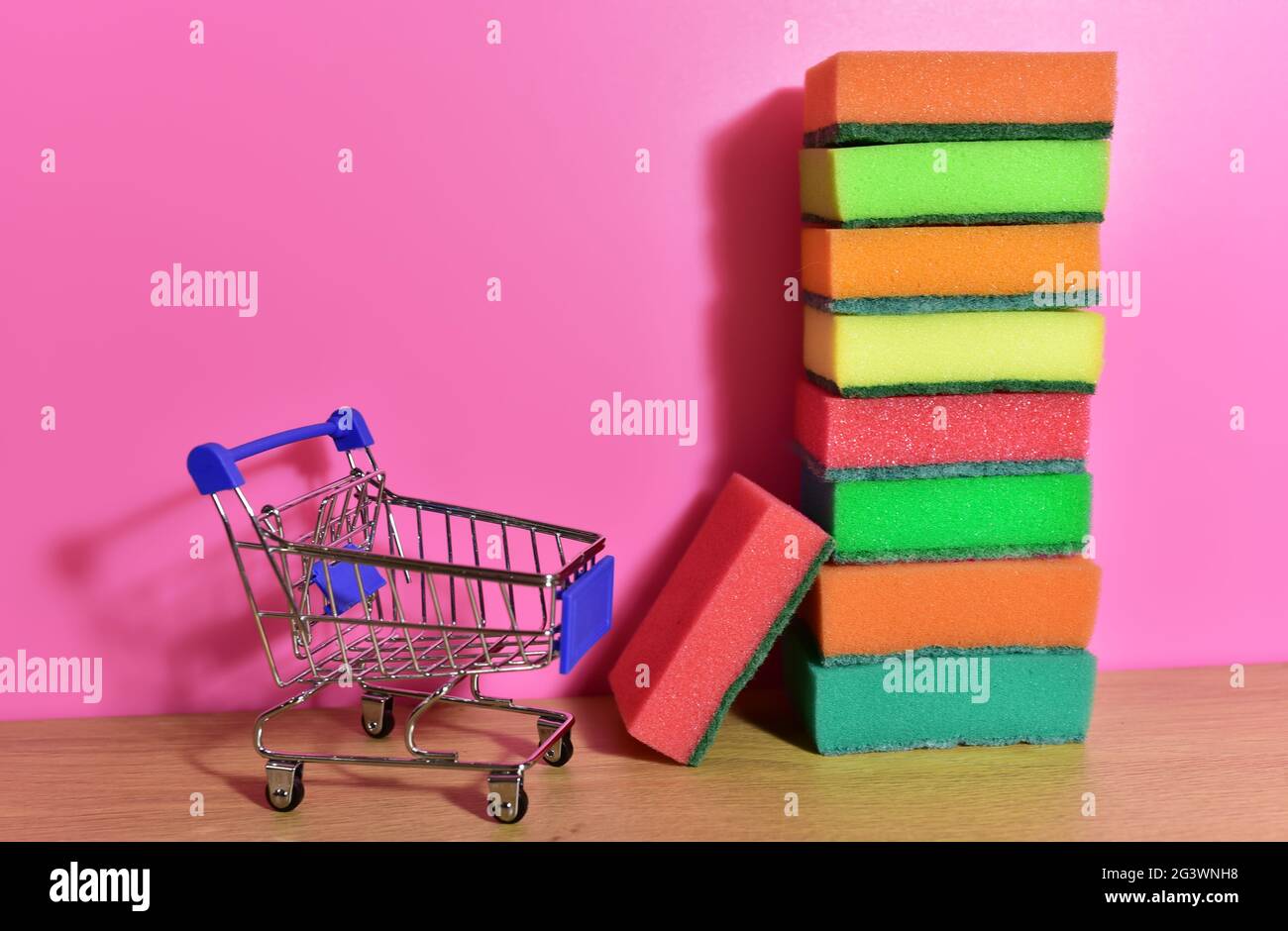 Sponge for washing dishes and plumbing in a shopping trolley on a pink ...