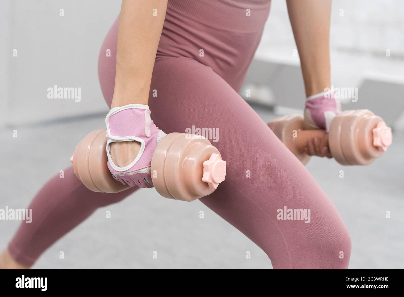 No face visible. Girl in a tight pink outfit working out with dumbbells ...