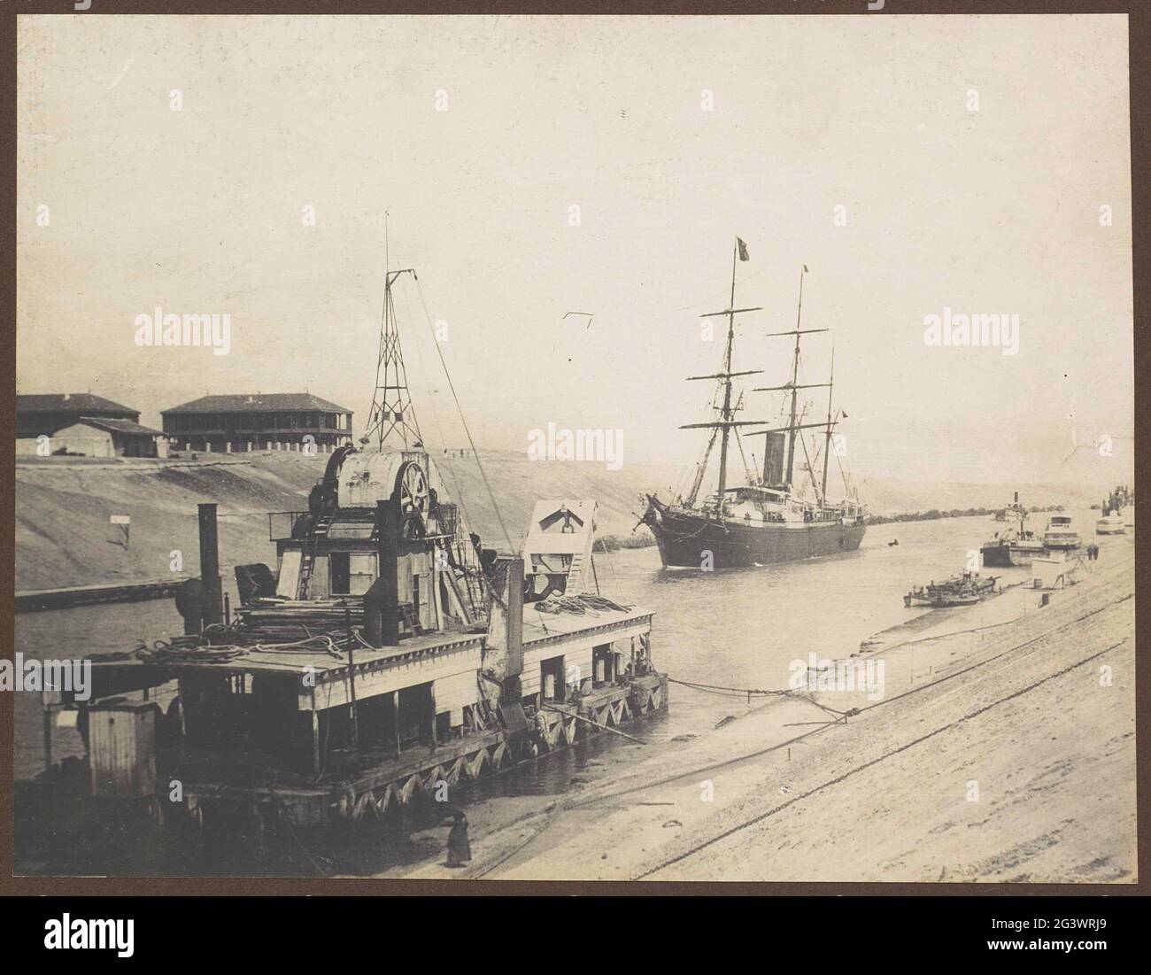 Ship sails through the Suez Canal at a dredger and houses. Part of ...