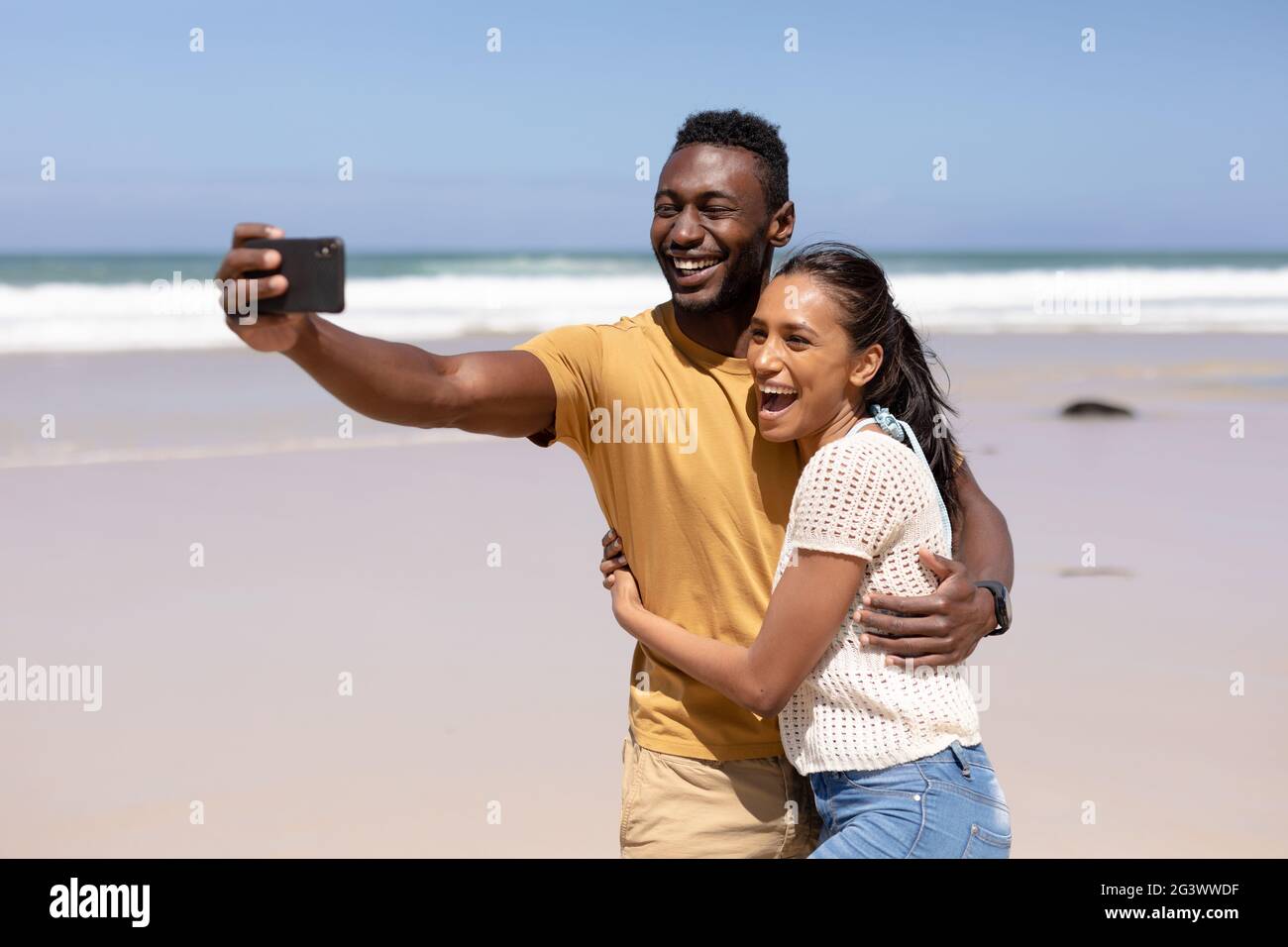 African american couple taking a selfie with smartphone on a beach by ...