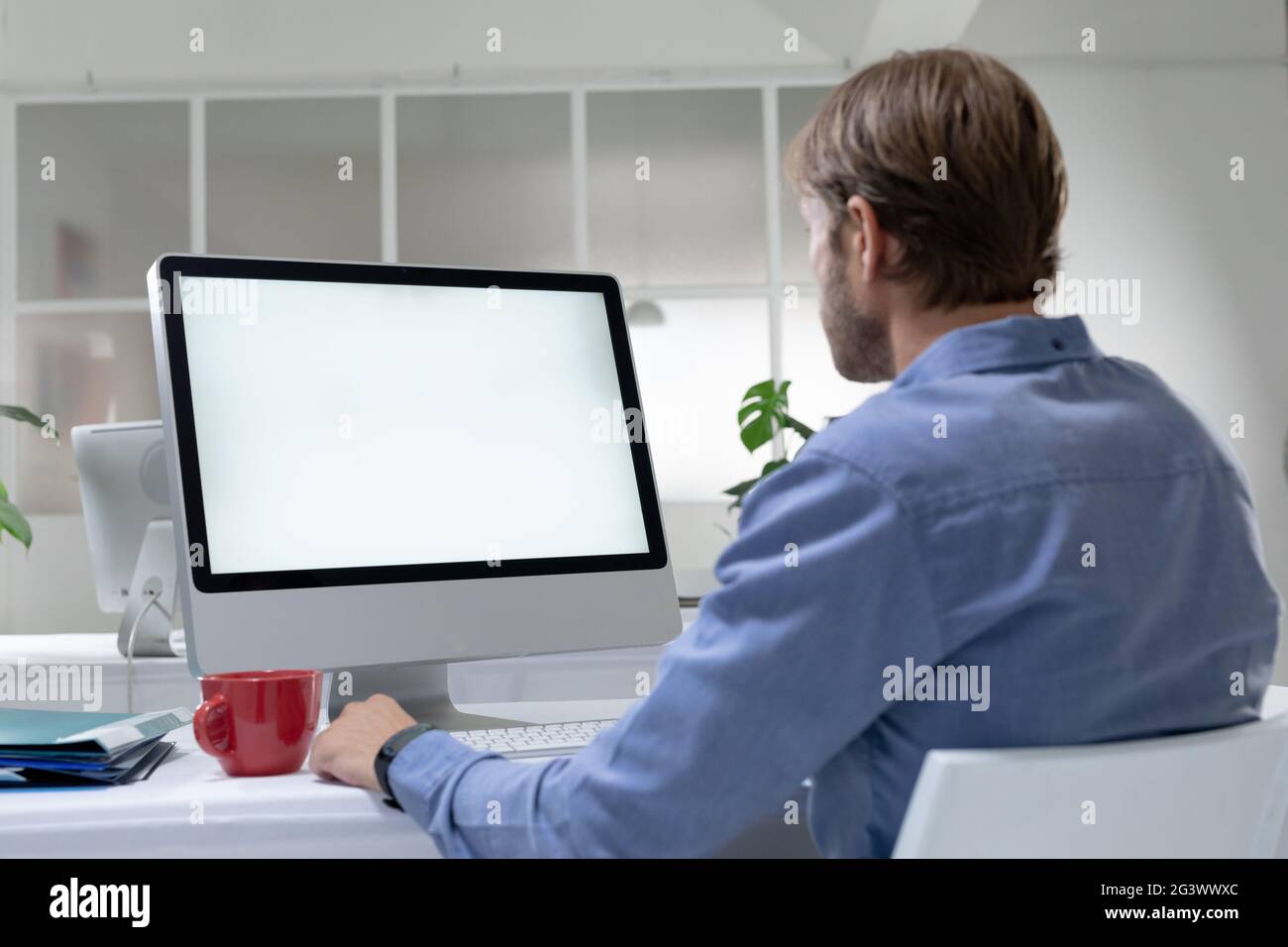 Rear view of caucasian businessman sitting at desk making video call ...