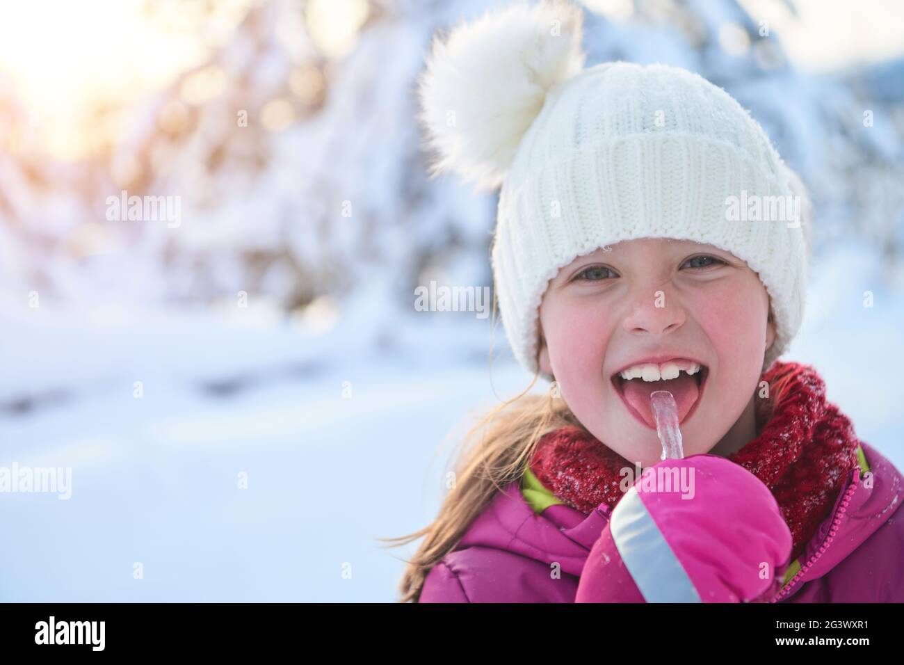 Cute little girl while eating icicle on beautiful winter day Stock ...