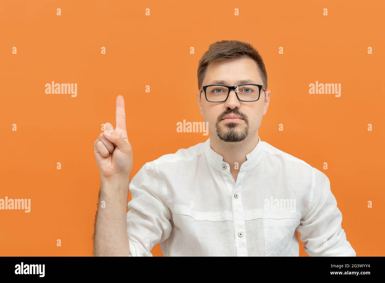 Young bearded thoughtful man in eyeglasses pointing his finger up ... Young bearded thoughtful man in eyeglasses pointing his finger up ...