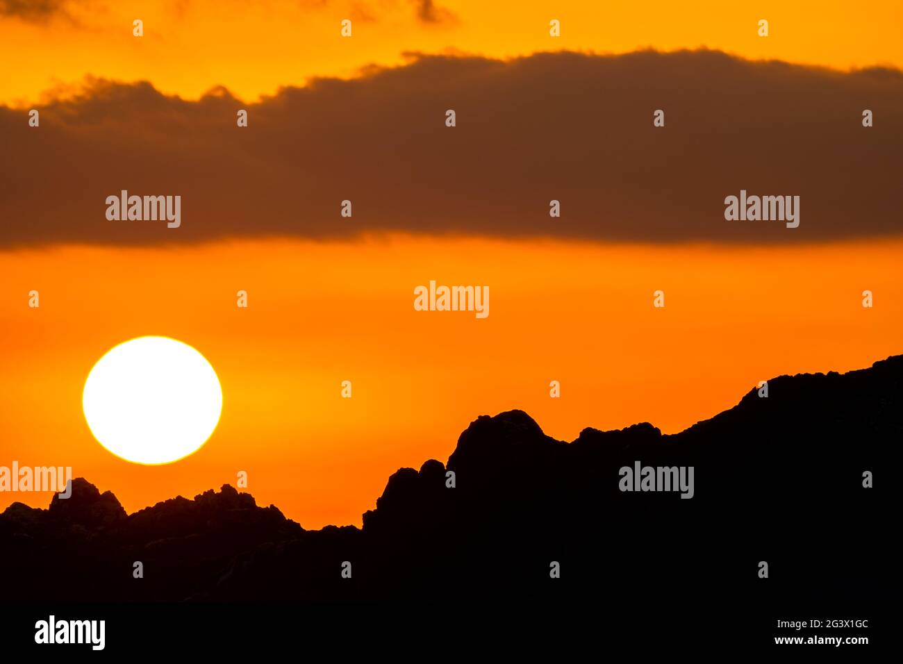 Sun in Orange Sky and Silhouette of Mountain Range Stock Photo - Alamy