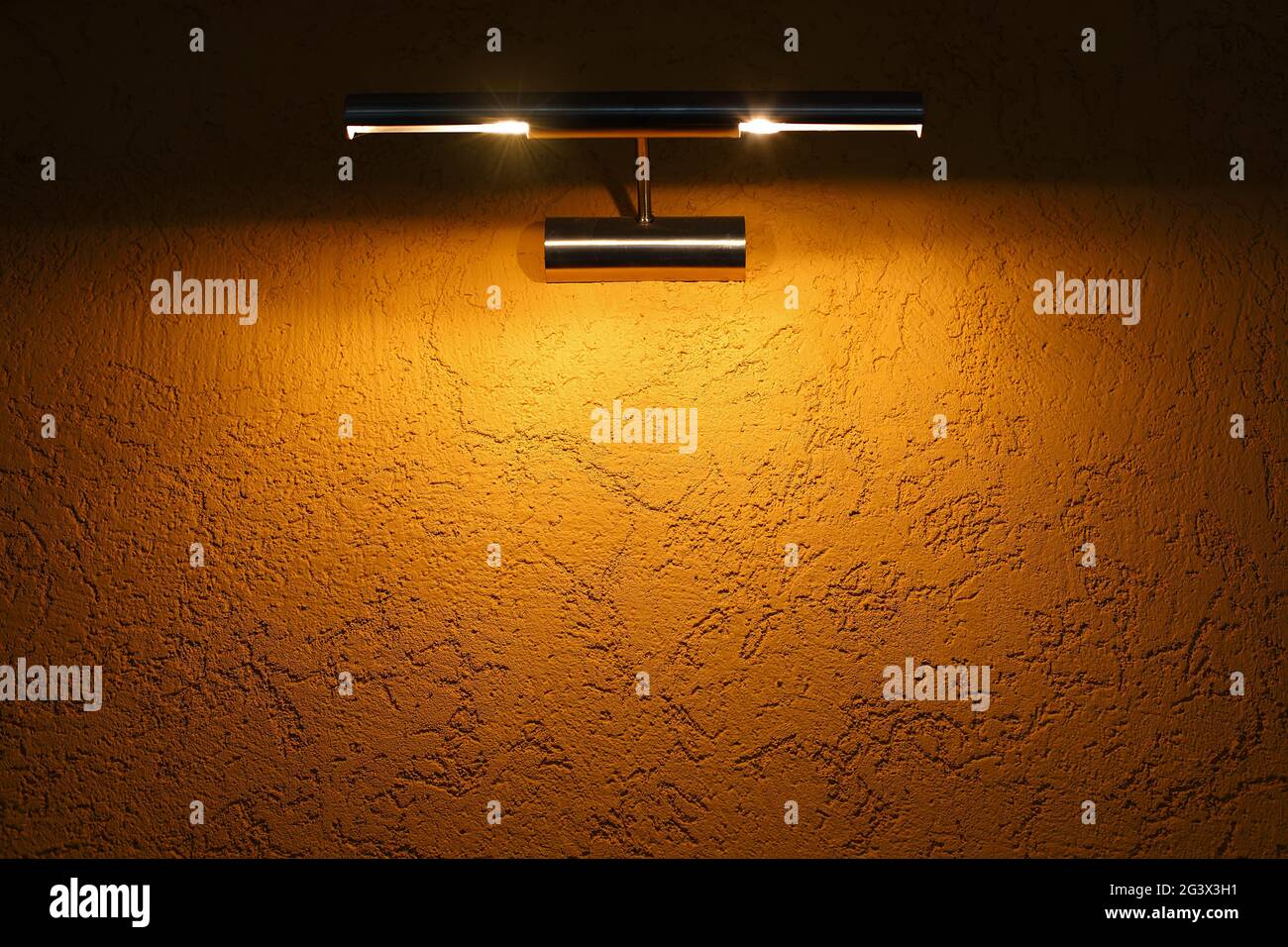 The yellow texture wall is illuminated by a light fixture on top Stock ...