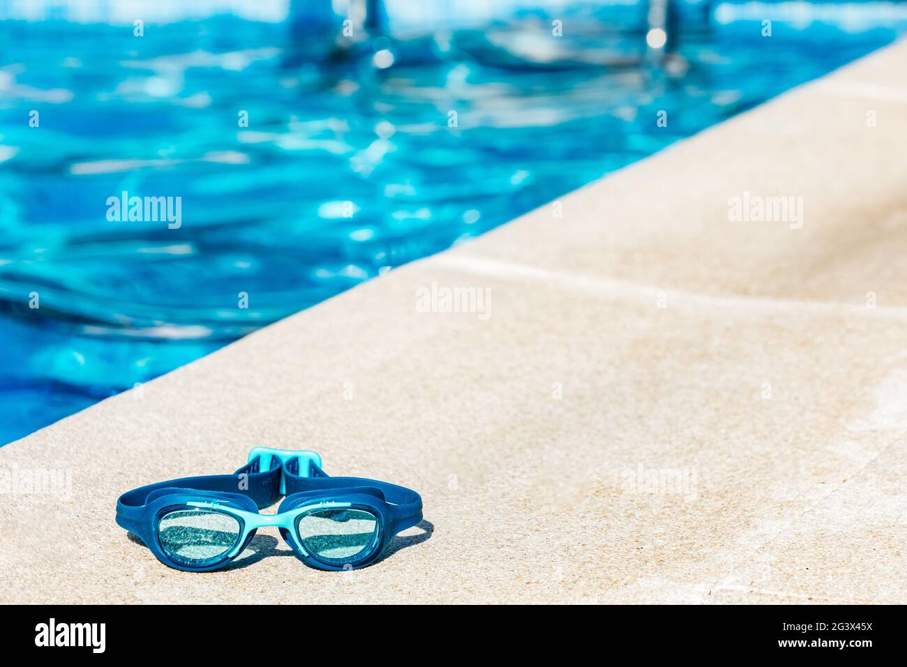 Blue swimming goggles on the curb of the pool, in the lower left corner ...