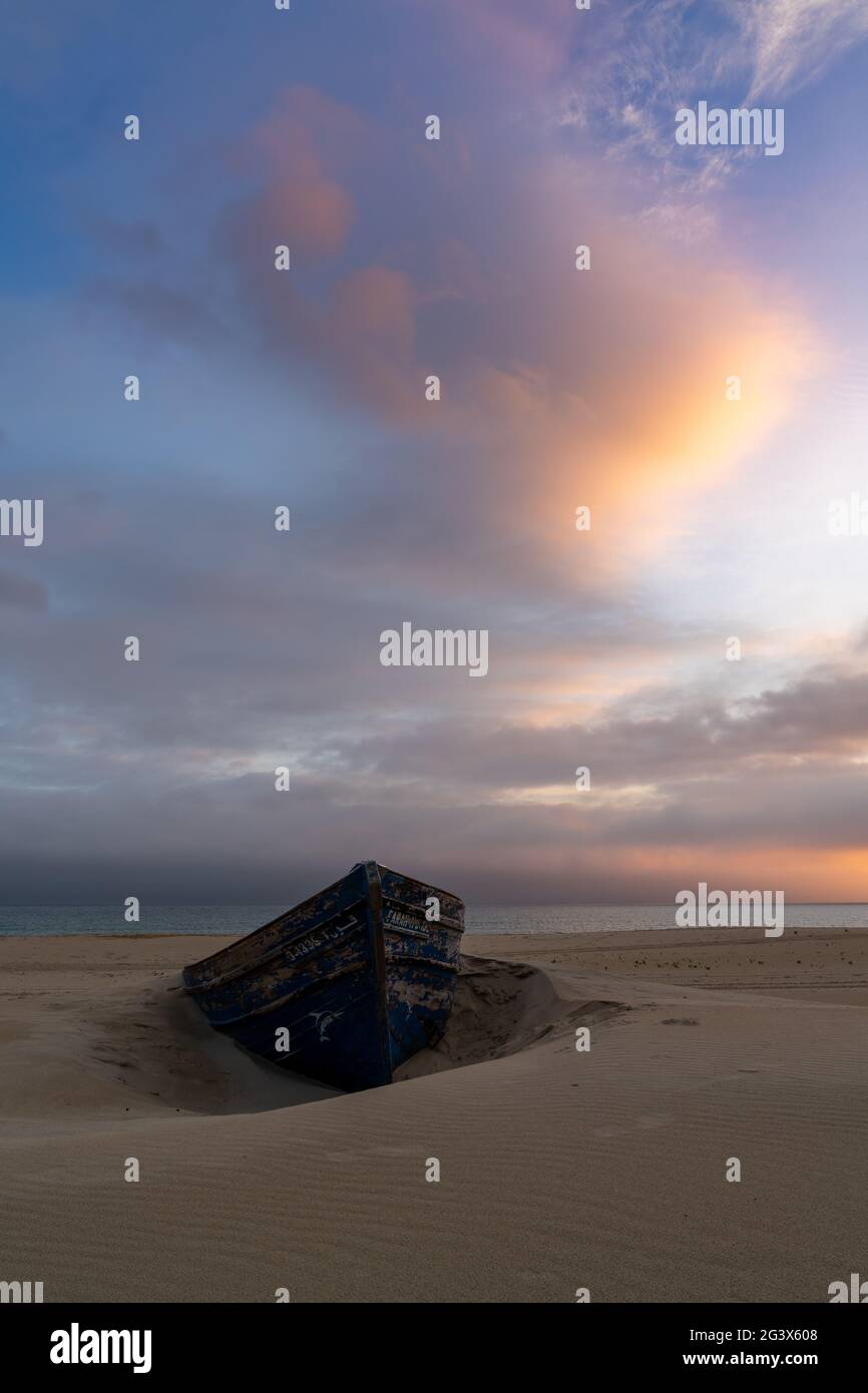 Wreck of an old wooden rowboat buried in the sand with a beautiful ...