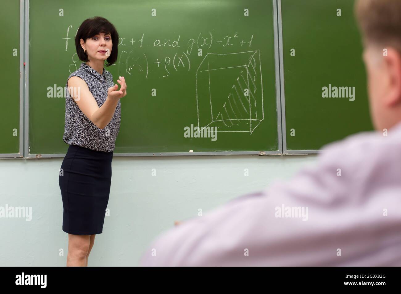 The teacher stands at the blackboard and asks student to answer with a ...