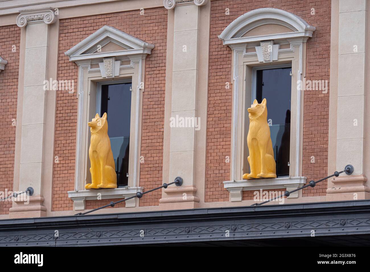 Two Sculptures of Yellow Wolves Leaning Against the Outside of Large ...