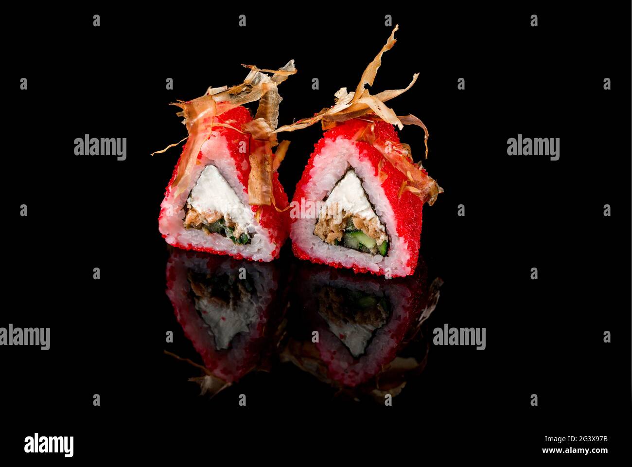 Two red tuna rolls with red caviar and shrimp on a black background ...