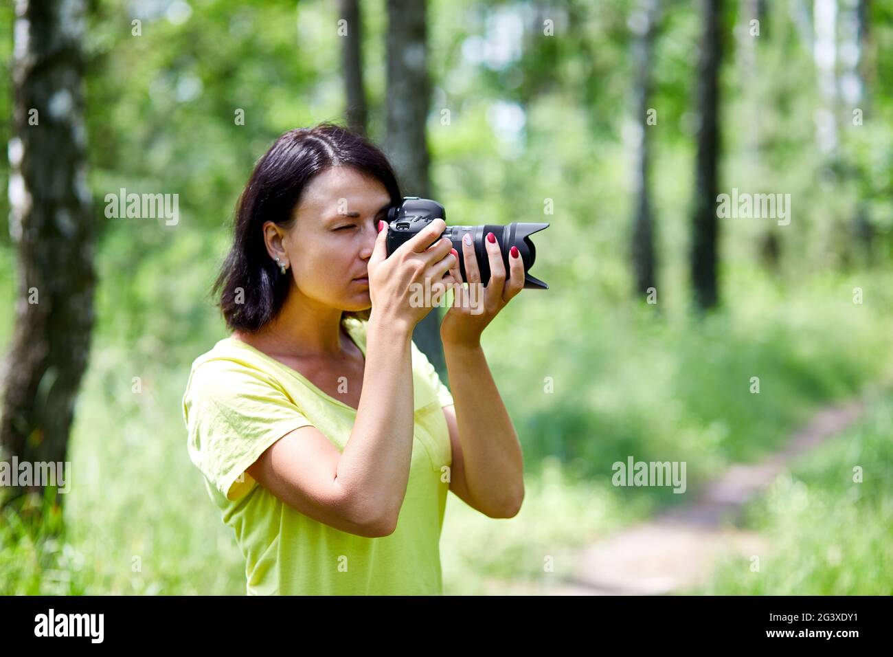 Portrait of a woman photographer covering her face with the camera ...